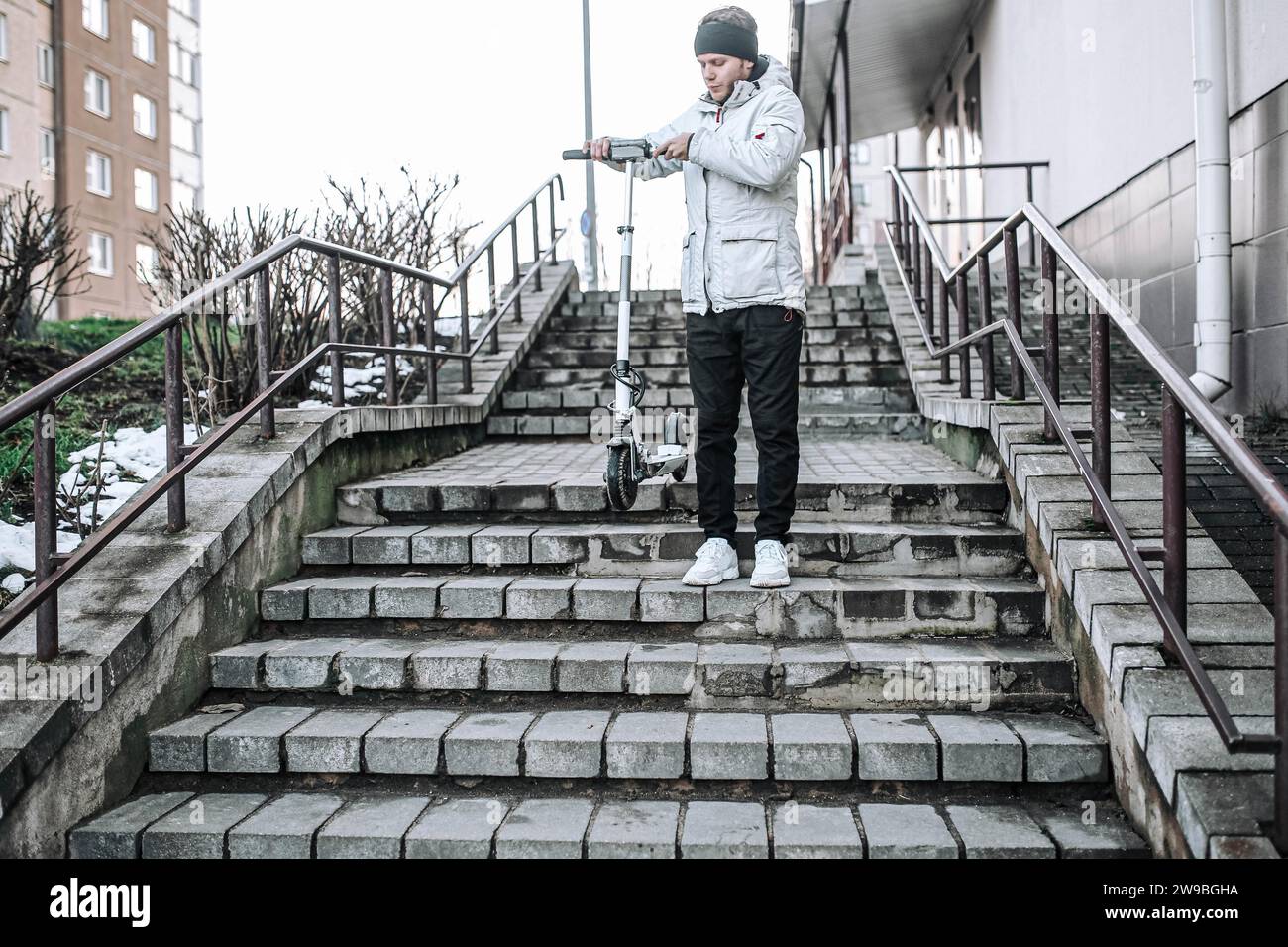 Young stylish guy lowering an electric scooter down the stairs Stock ...
