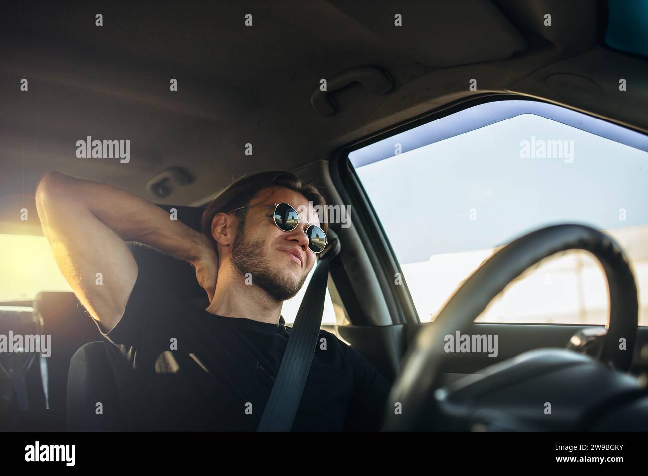 Young handsome male driver tired of sitting behind the wheel, neck pain ...