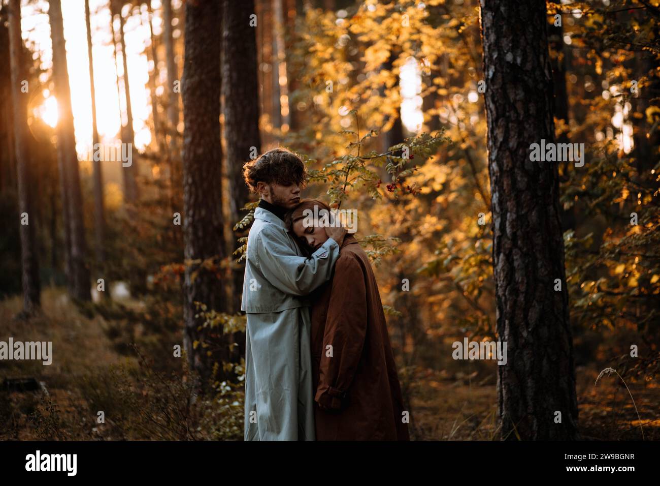 Beautiful fashionable couple in love in the forest at sunset in autumn ...
