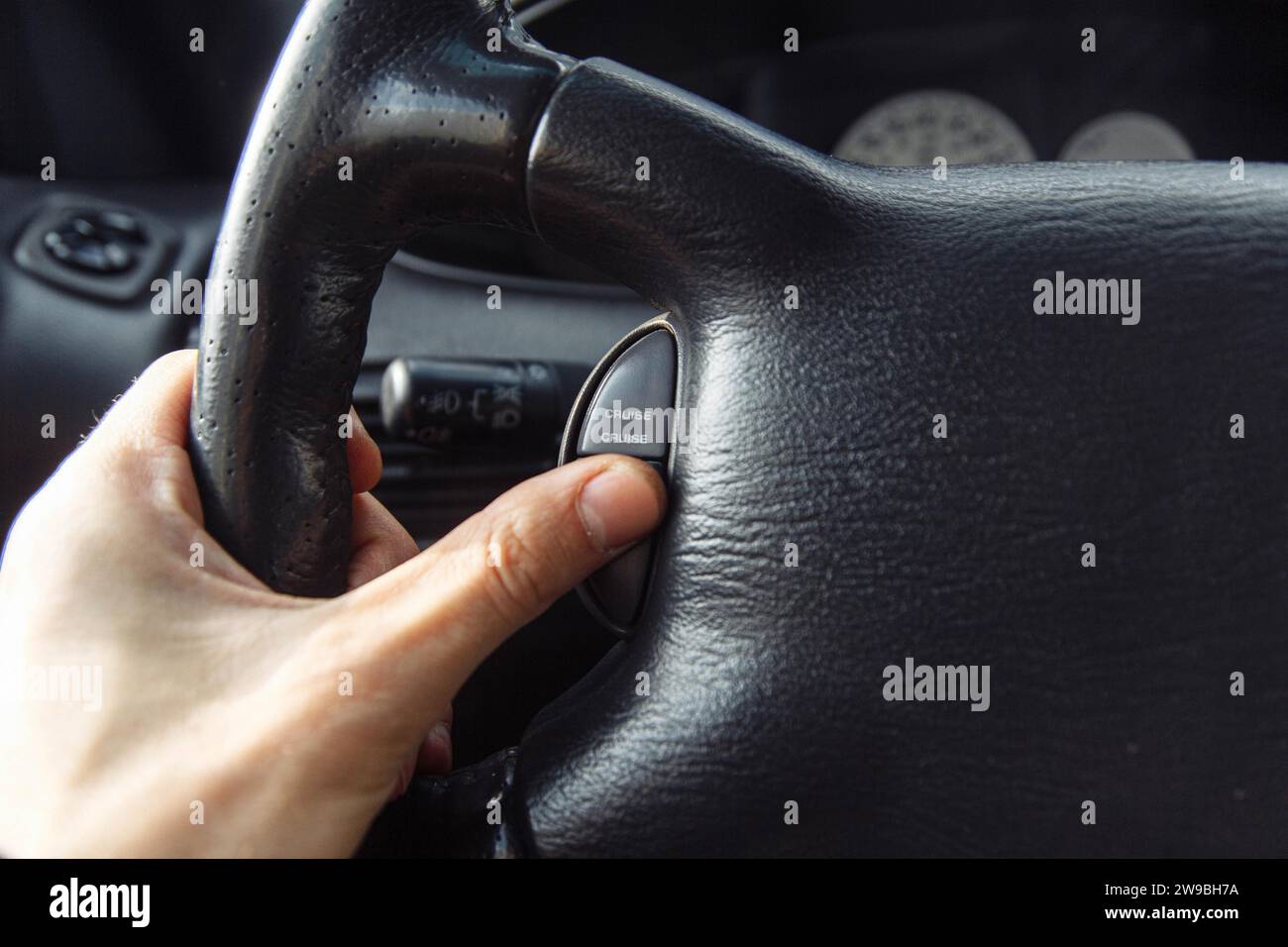 A man is driving a premium car, his hand is on the steering wheel, he ...