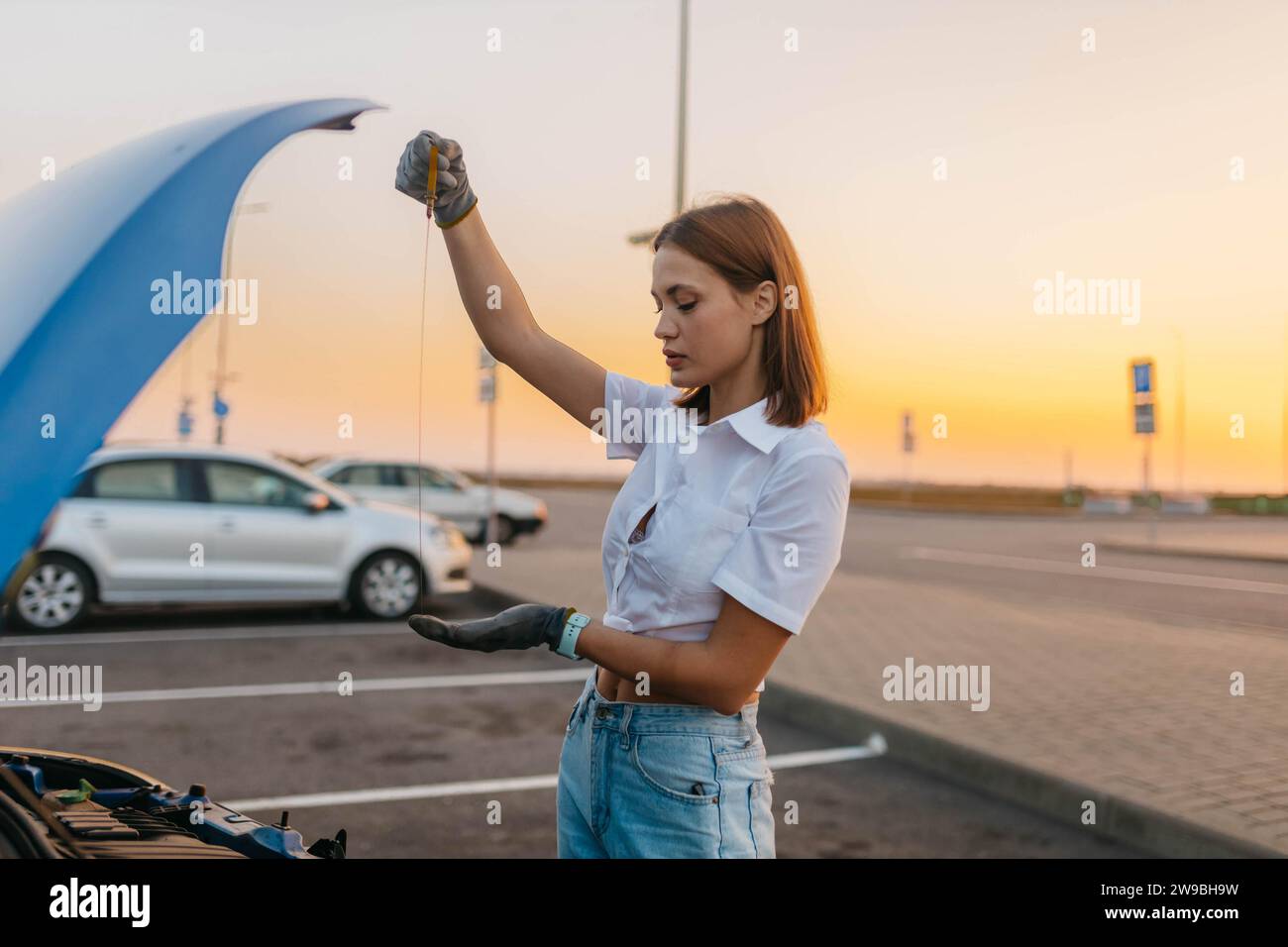 Young beautiful hot girl driver checks oil level, business trip ...