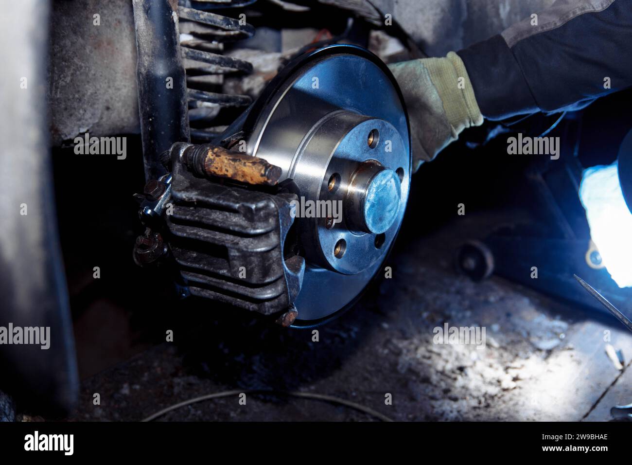 Installing a new brake disc on a car hub, mechanic, glove, screws ...