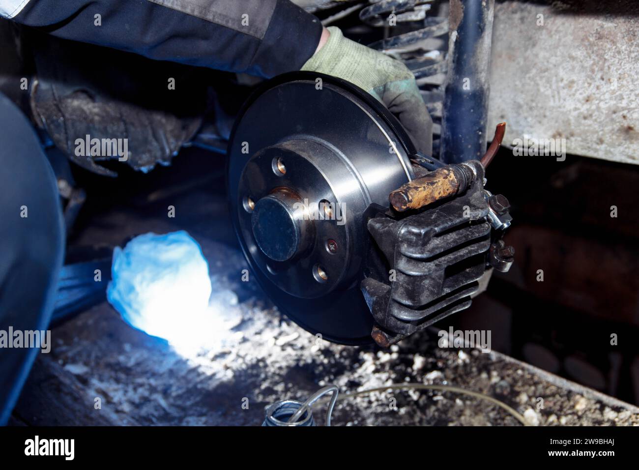 Installing a new brake disc on a car hub, mechanic, glove, screws ...