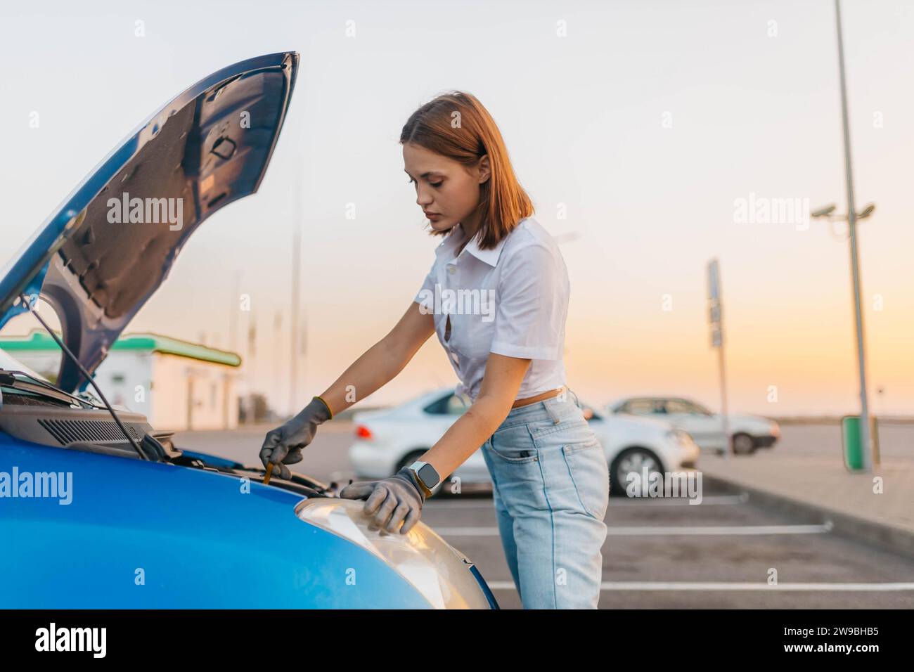 Young beautiful hot girl driver checks oil level, business trip ...
