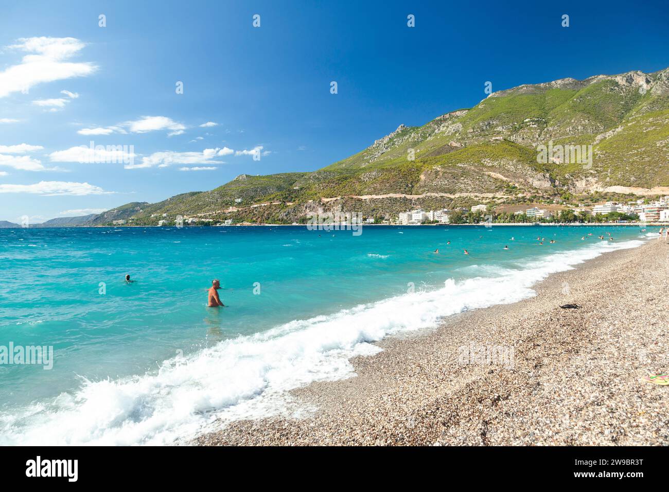 People enjoying the sun and turquoise waters at the beach of Loutraki ...