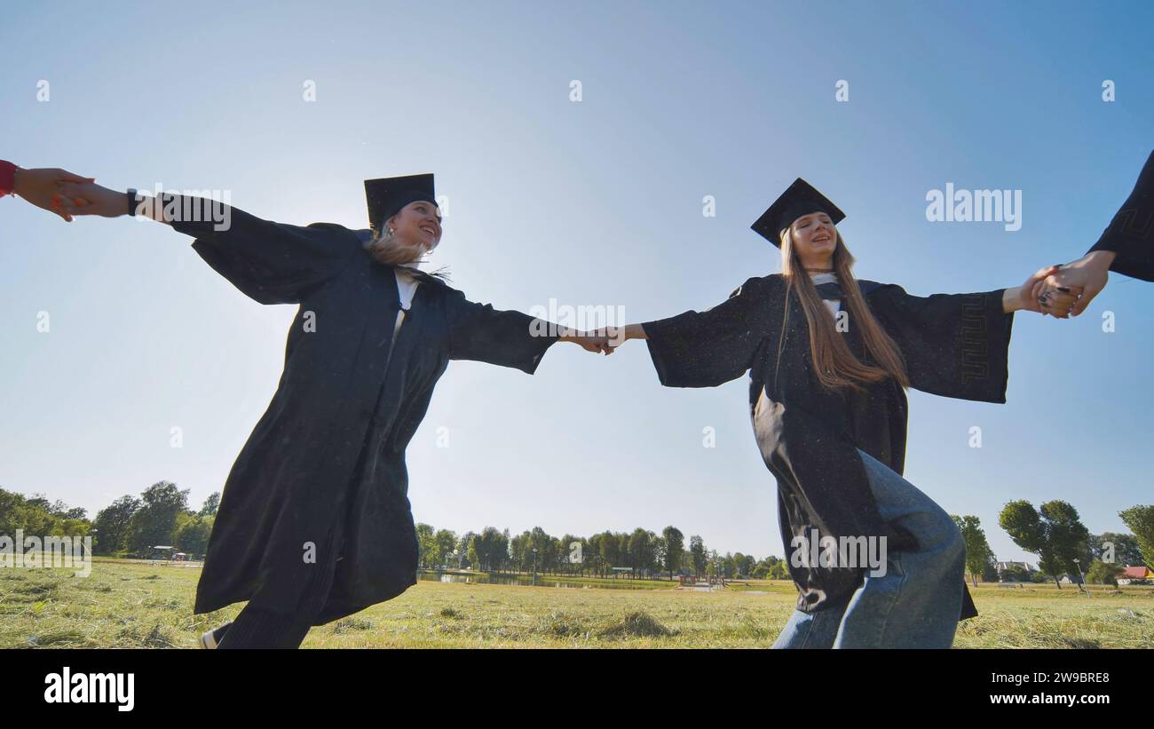 College graduates holding hands run in a round dance Stock Photo - Alamy