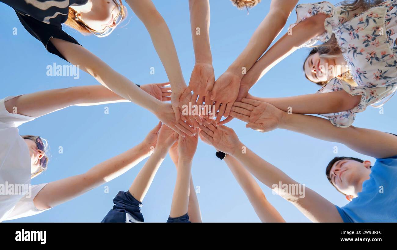 Friends putting their hands together in a sign of unity and teamwork ...