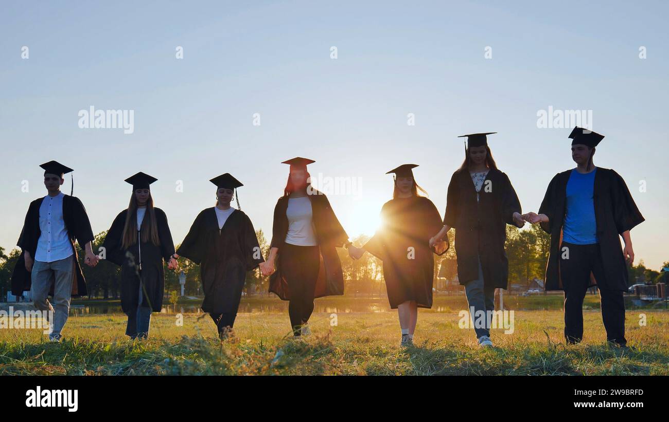 College graduates walk at sunset holding hands Stock Photo - Alamy