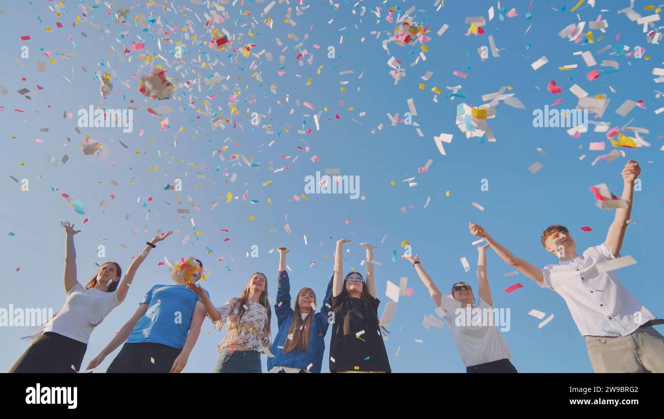 Friends toss colorful paper confetti from their hands Stock Photo - Alamy