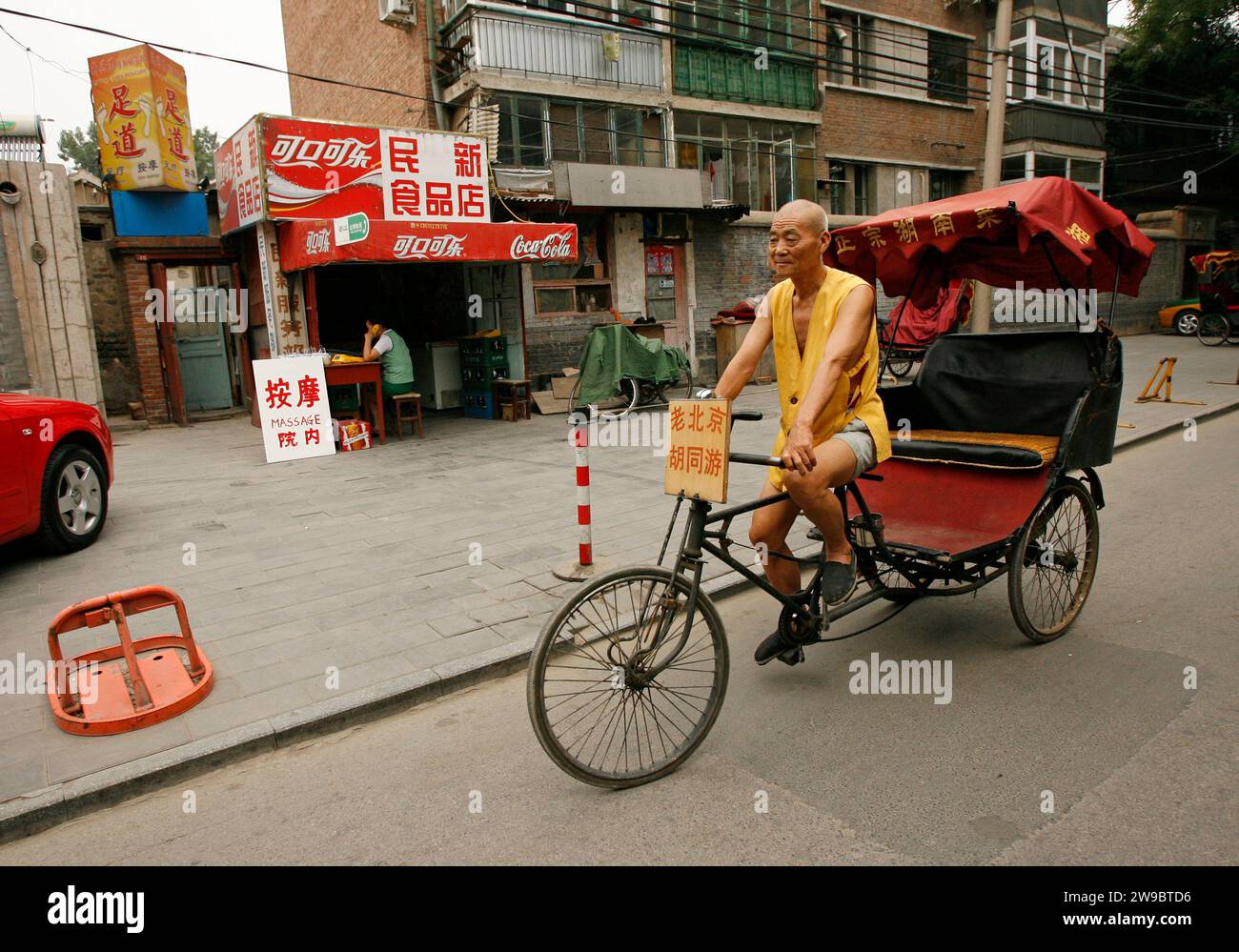 A bicycle rickshaw driver makes his way through one of the Beijing's ...
