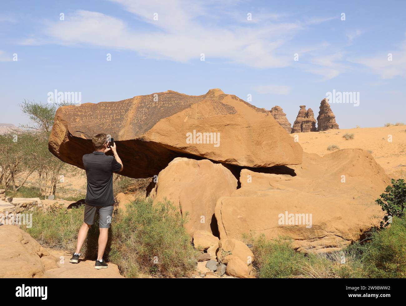 Tourist photographing the ancient inscriptions at Jabal Ikmah on a tour ...