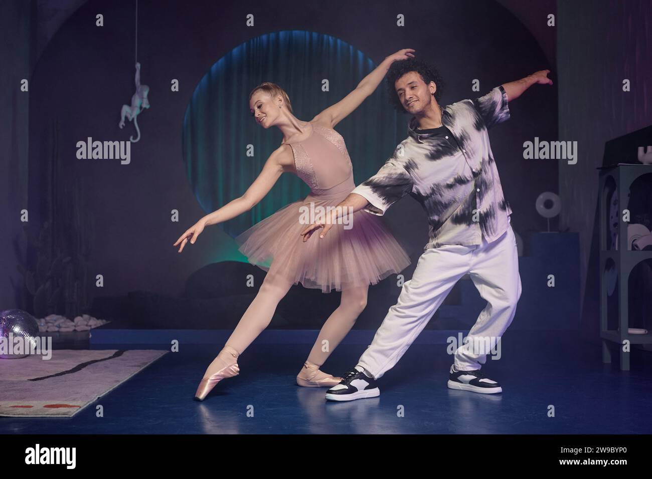 Wide shot of ballerina demonstrating ballet figure, young stylish man ...