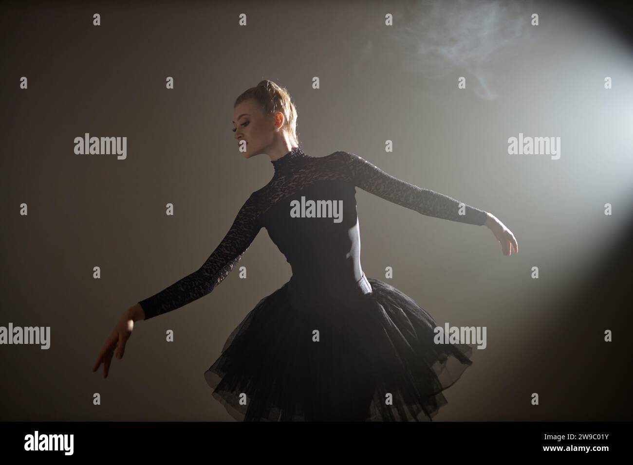 Young caucasian ballerina in black lace dress demonstrating ballet ...
