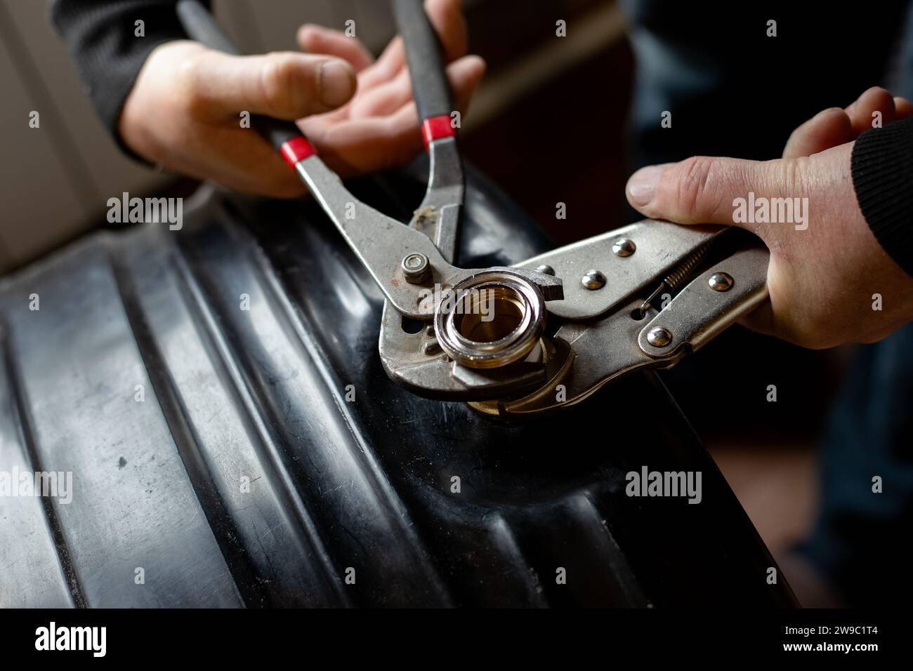 A plumber screws a fitting onto a water tank. Installation of a summer ...