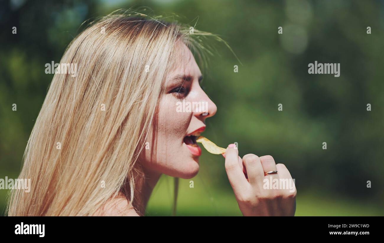 Blonde girl eating chips on the street Stock Photo - Alamy