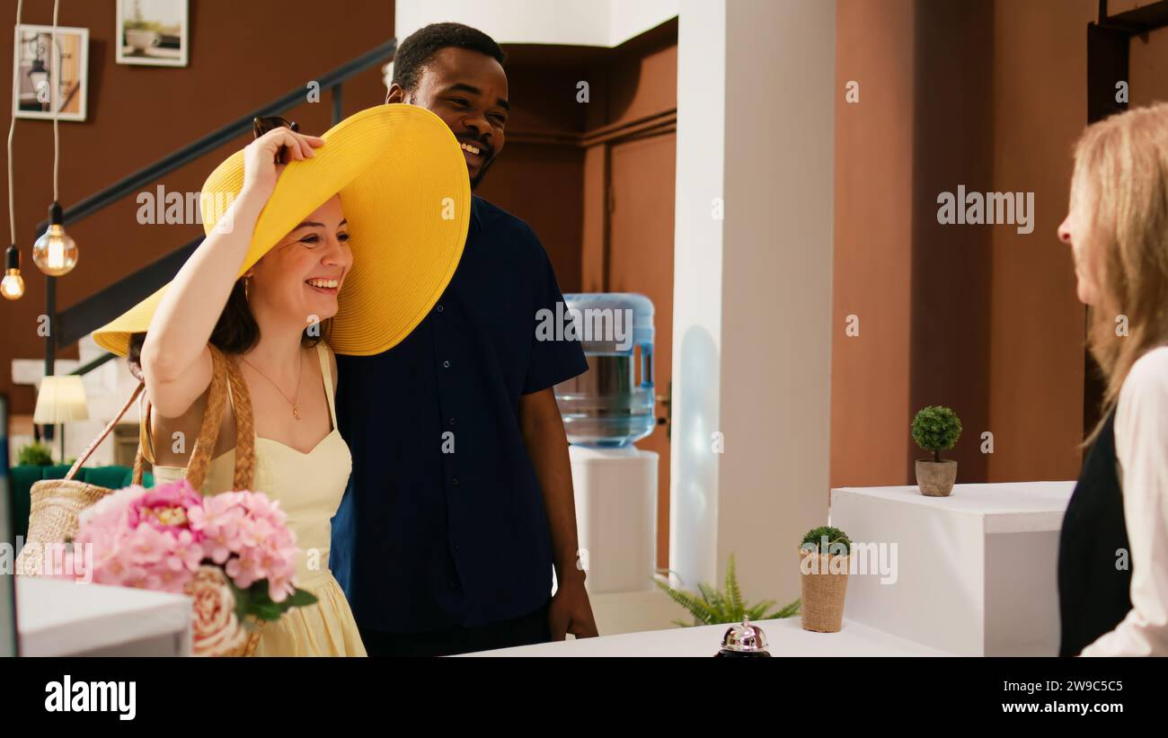 Diverse couple entering hotel lobby with luggage, arriving on seaside ...