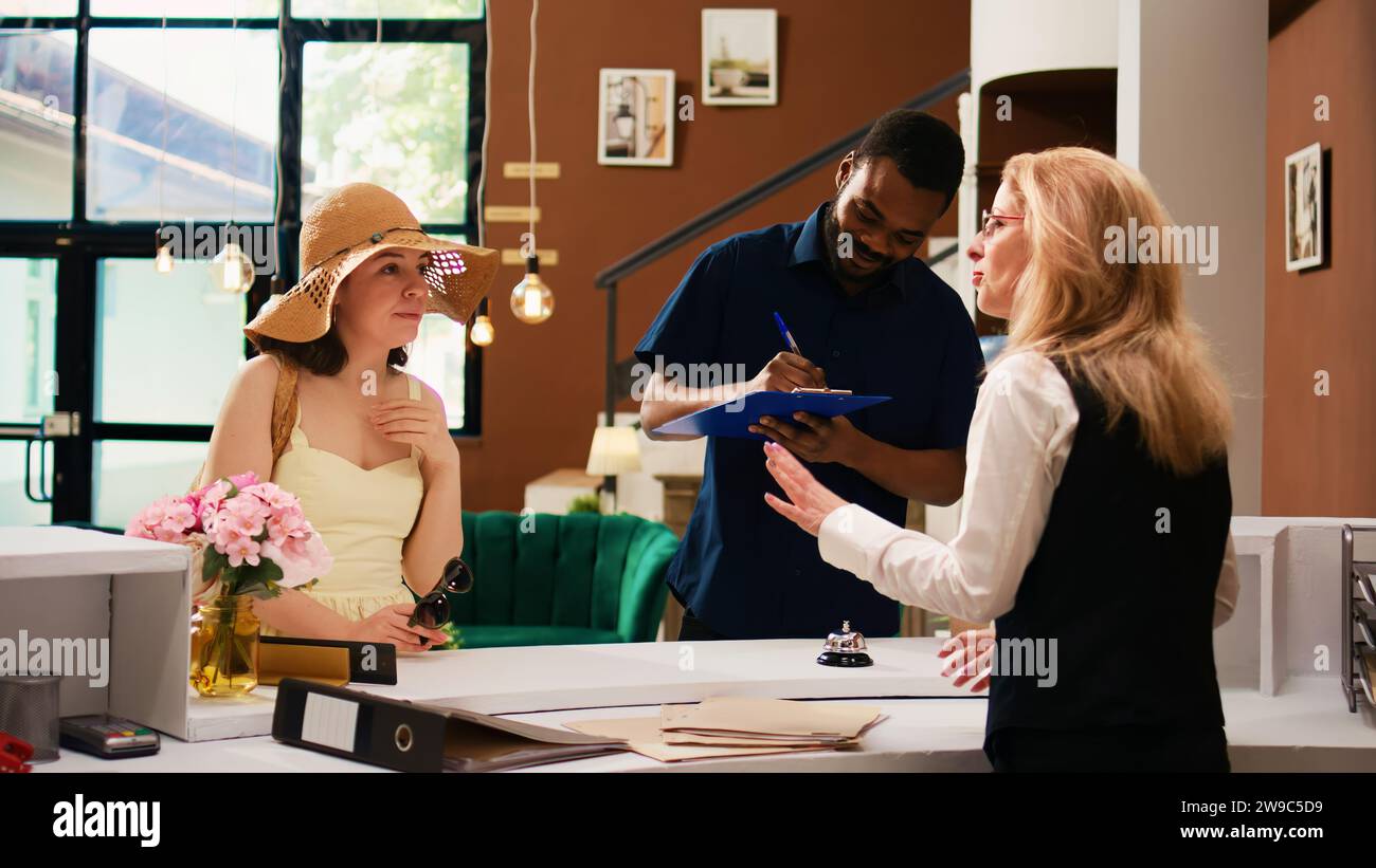 Guests filling in registration papers at reception, doing check in ...