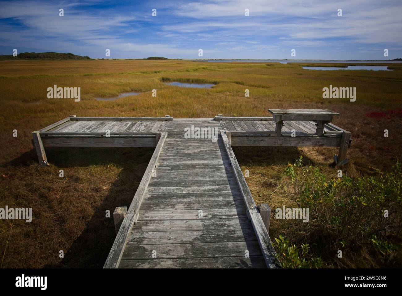 A weathered wooden viewing platform over looking a marsh which land on ...