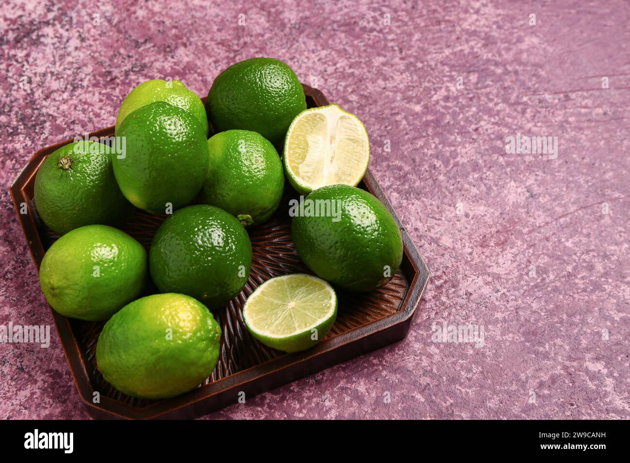 Tray with fresh limes on purple background Stock Photo - Alamy