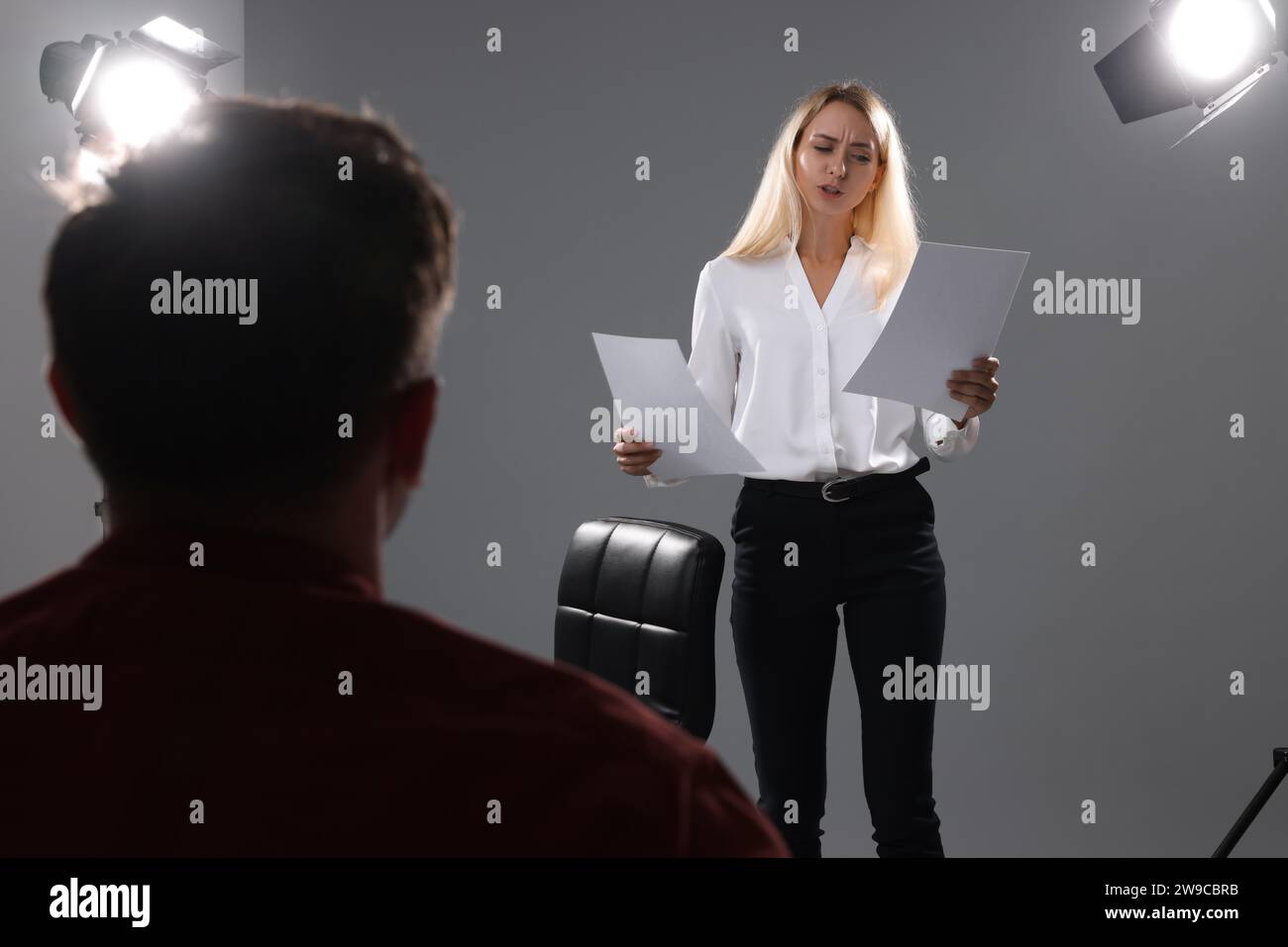 Emotional woman with script performing in front of casting director ...