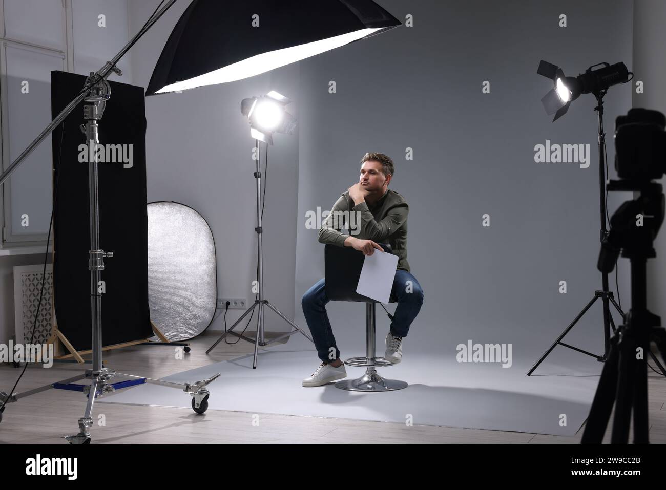 Casting call. Man with script sitting on chair against grey background ...