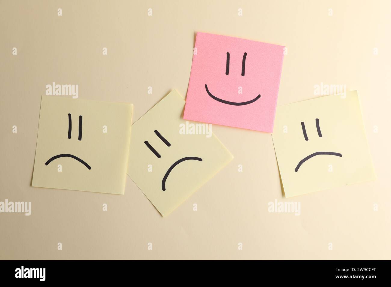 Choice concept. Pink sticky note with happy emoticon among yellow ...