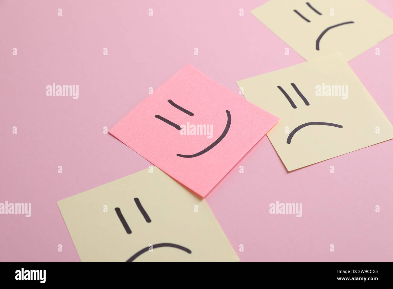 Choice concept. Sticky note with happy emoticon among beige papers with ...