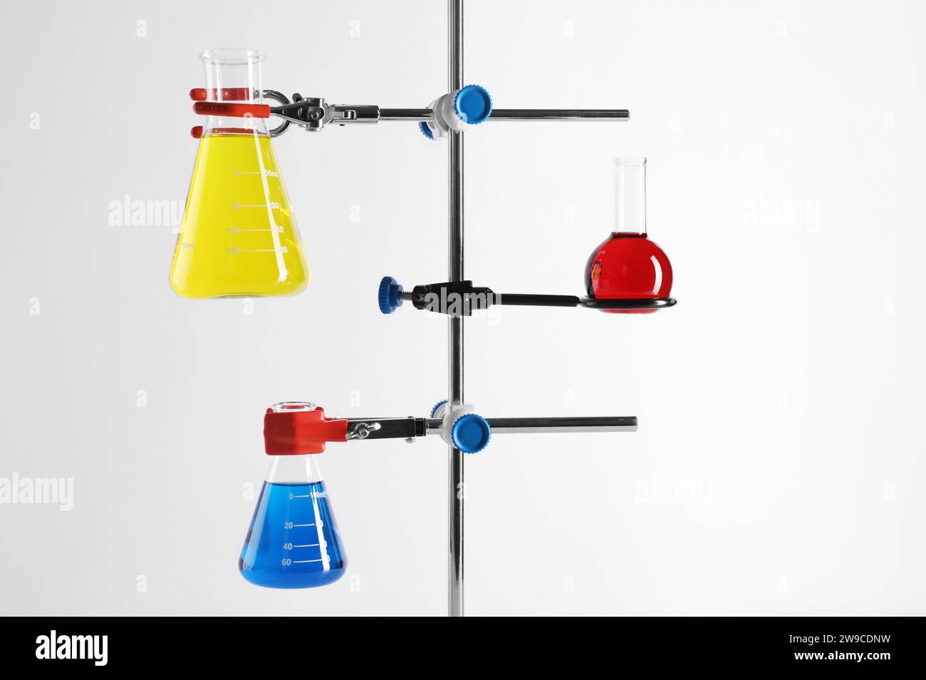 Retort stand and laboratory flasks with liquids on white background ...
