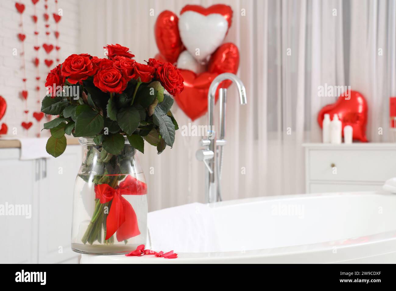 Bathtub with bouquet of beautiful red roses in bathroom. Valentine's ...