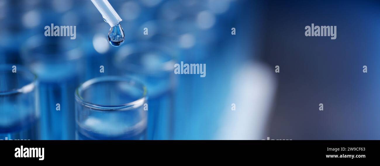 Laboratory analysis. Dripping reagent into test tube against blurred ...