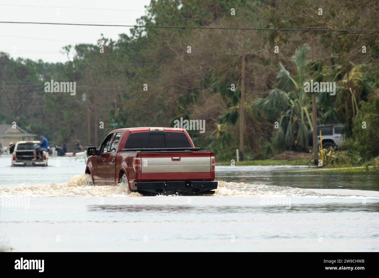 Hurricane flooded street with moving cars in surrounded with water ...