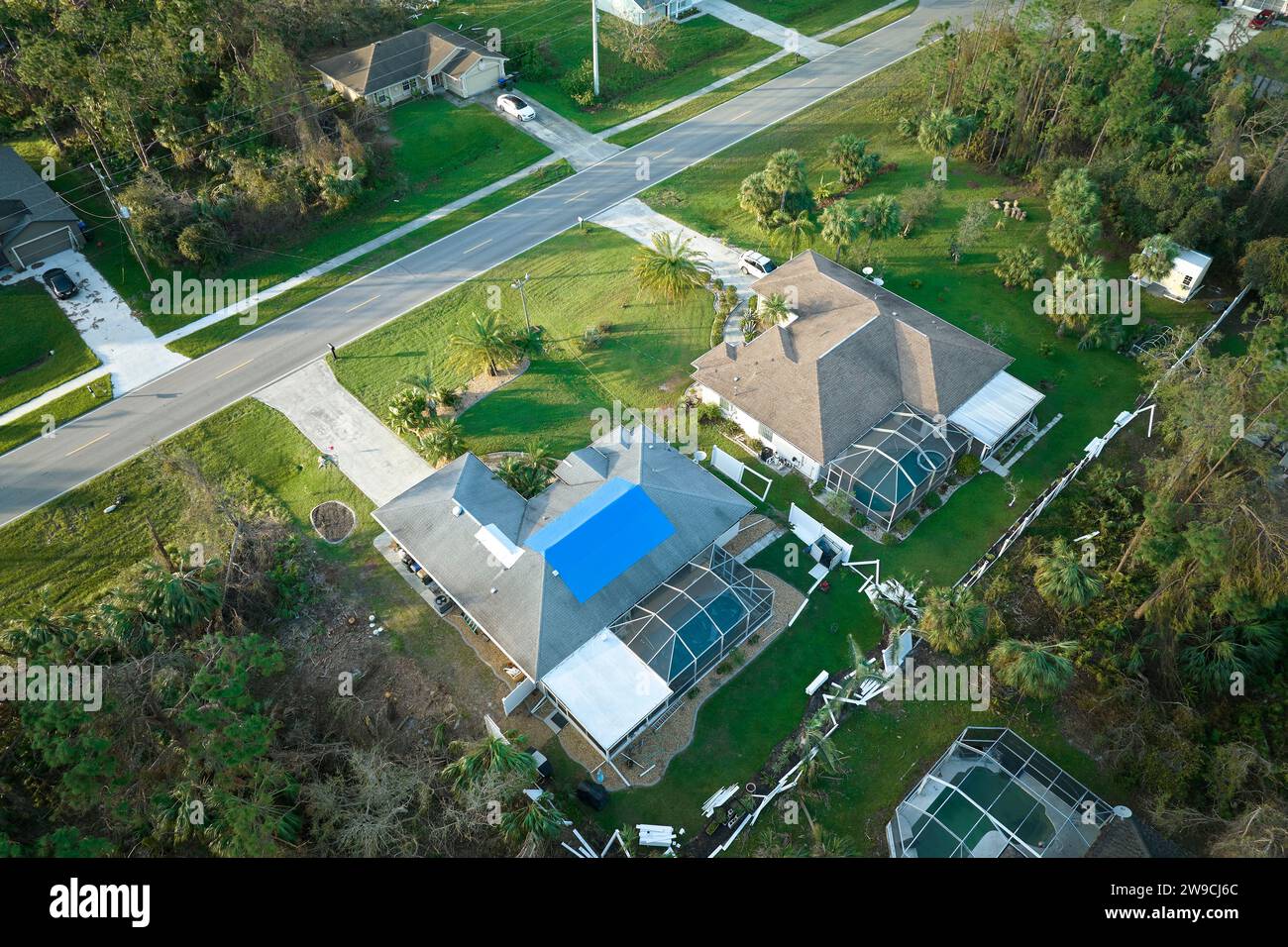 Aerial view of damaged in hurricane Ian house roof covered with blue ...