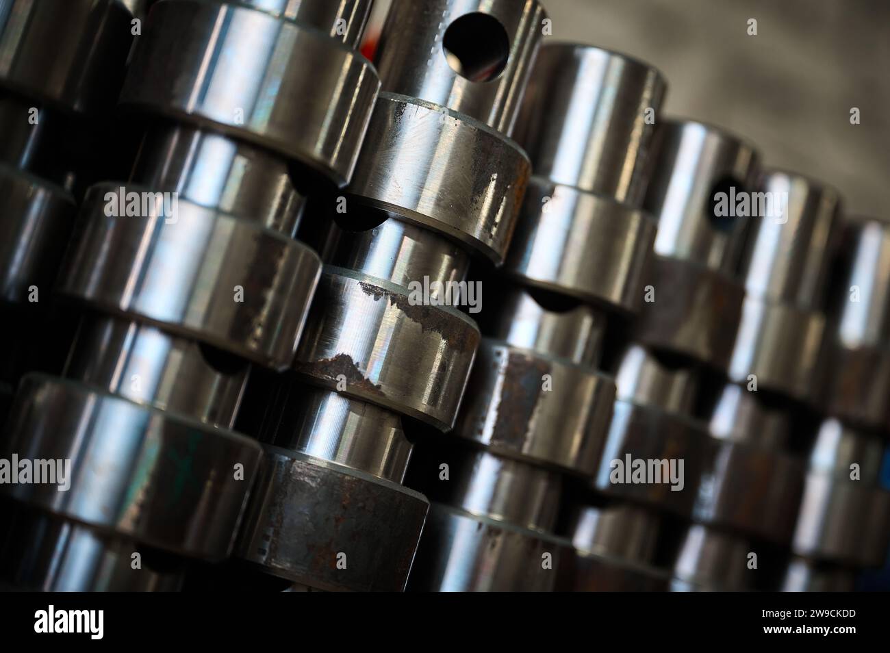 Stacks of steel rollers with holes in plant warehouse Stock Photo - Alamy