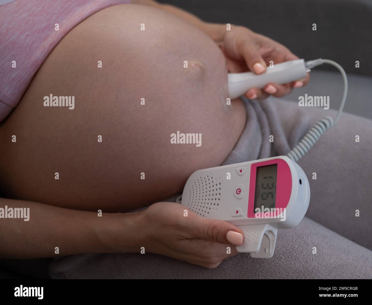 Close-up of a pregnant woman's belly using a home doppler. Normal baby ...