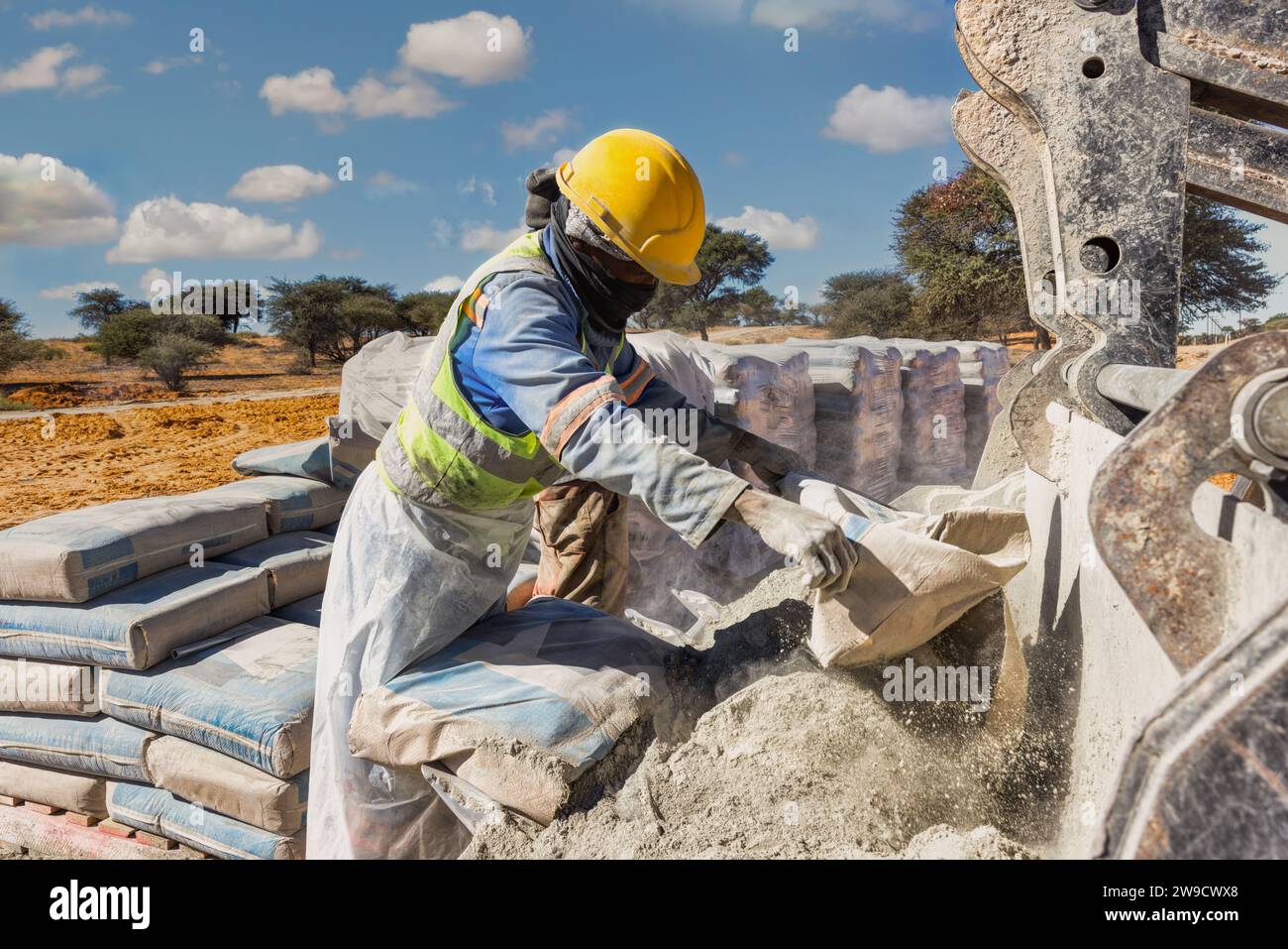 african american construction worker loading cement bags in a backhoe ...