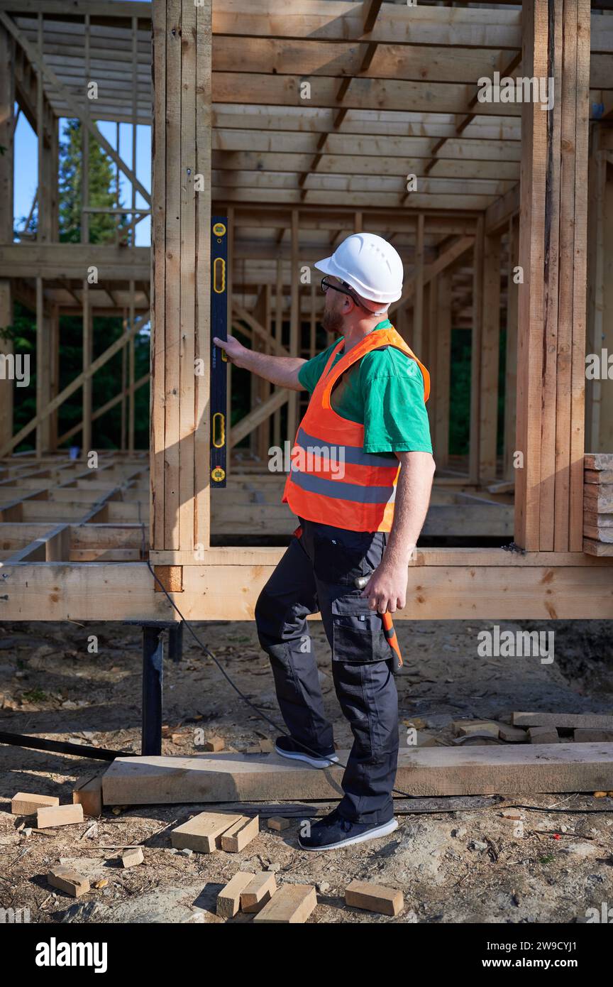Carpenter constructing two-storey wooden frame house. Man inspects ...
