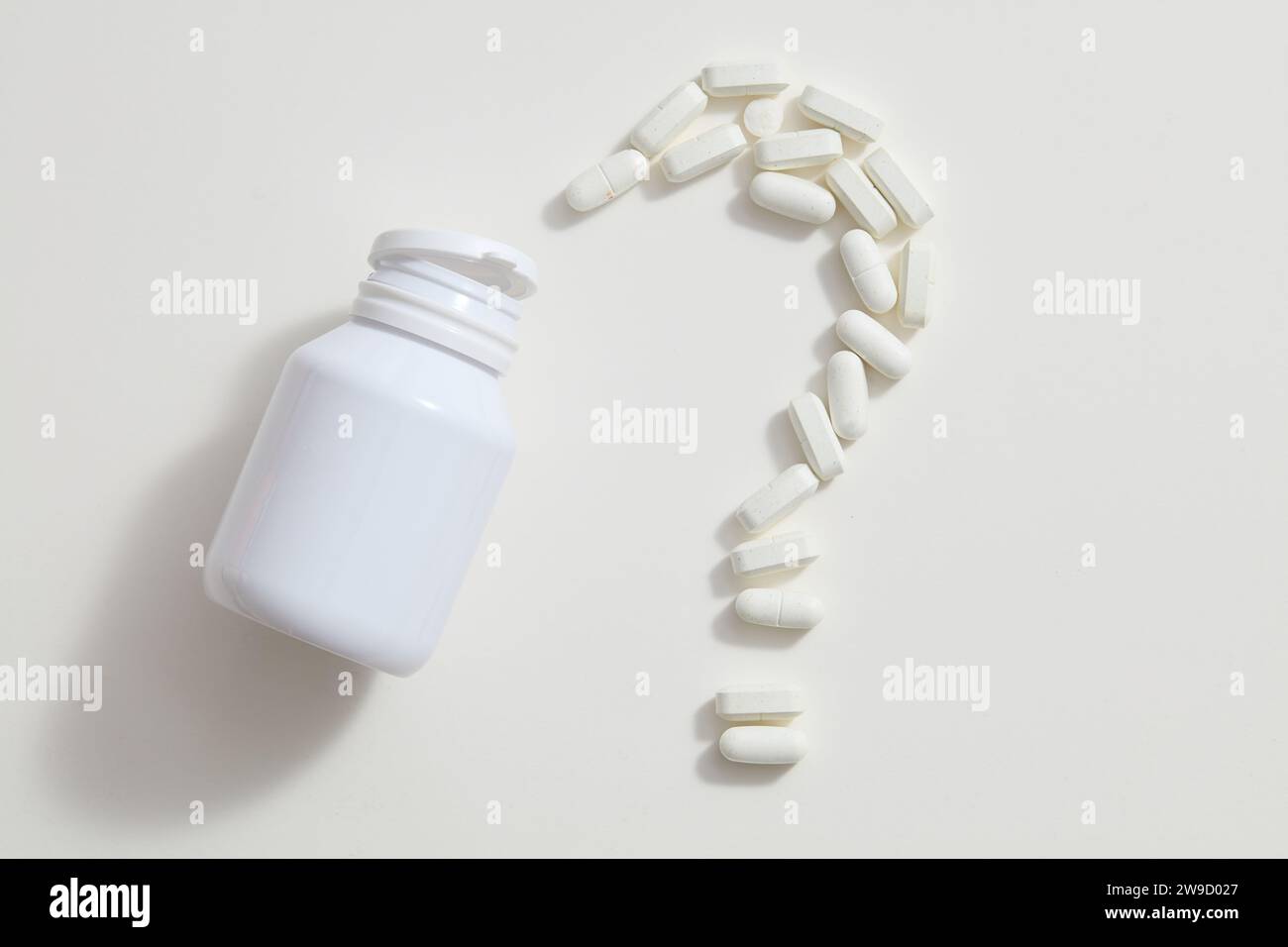 An unlabeled white bottle next to pills arranged in the shape of a ...