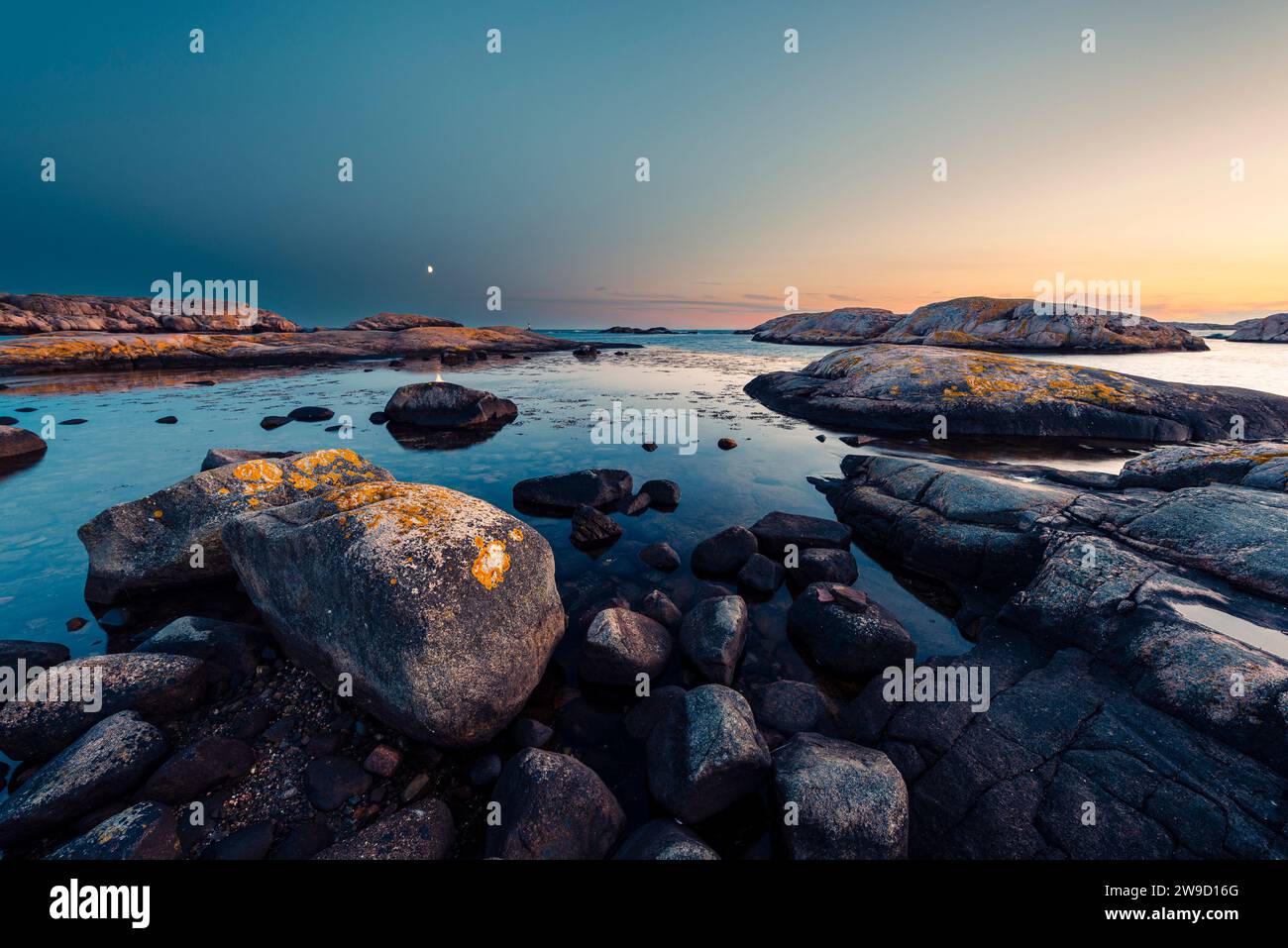 Moon in the glowing sunset over rocks in the nature reserve Tjurpannan ...
