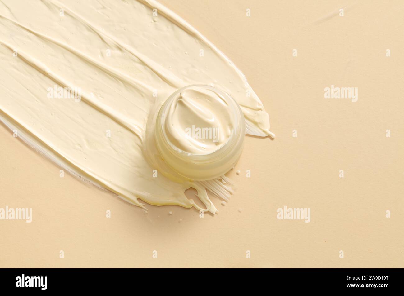 Flat lay of a unmarked jar streaks of cream with an pastel color ...
