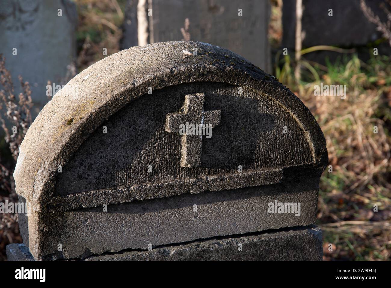 Old and worn tombstone with a Catholic cross Stock Photo - Alamy