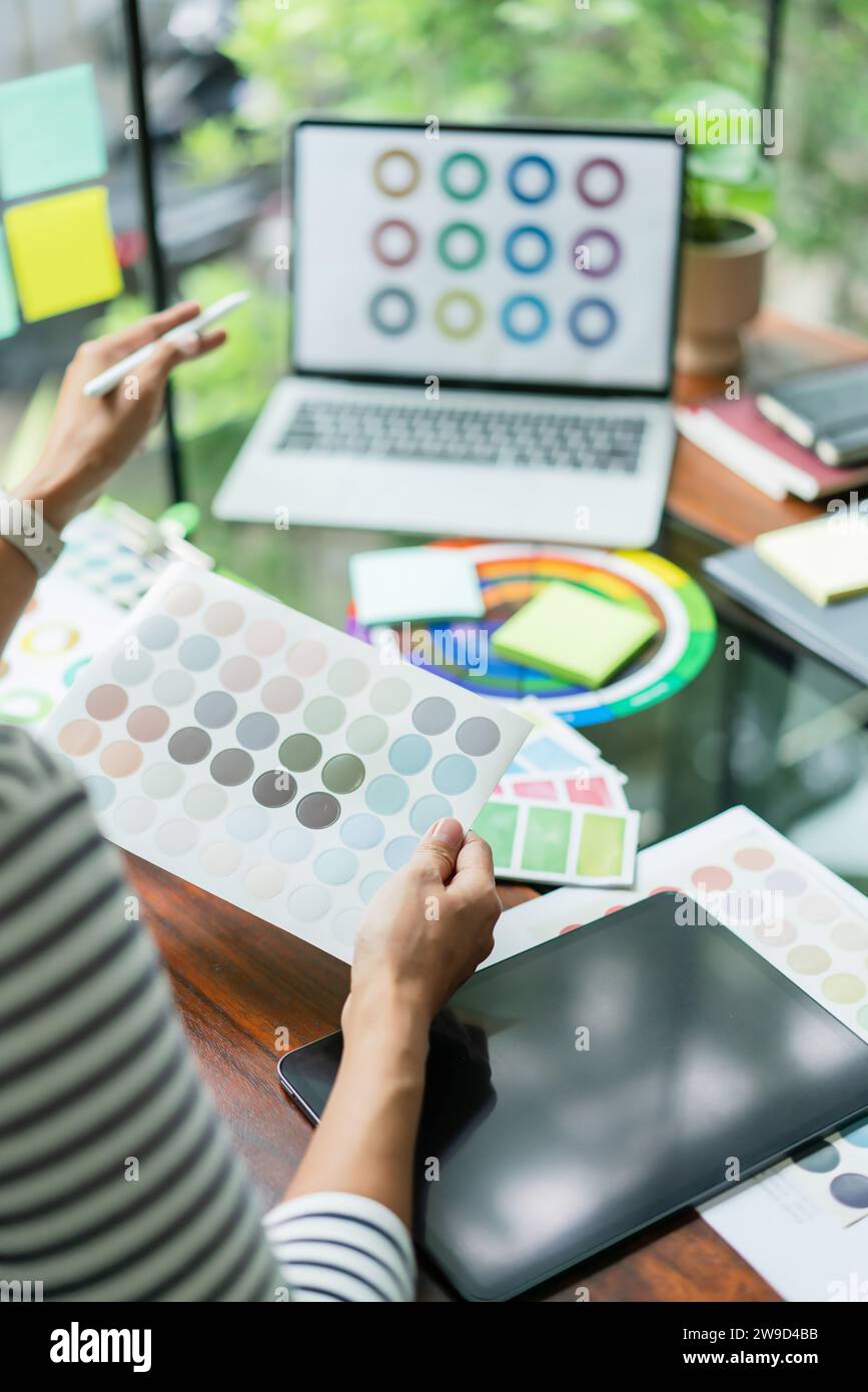 Creative graphic designer holding color swatch and comparing color on ...