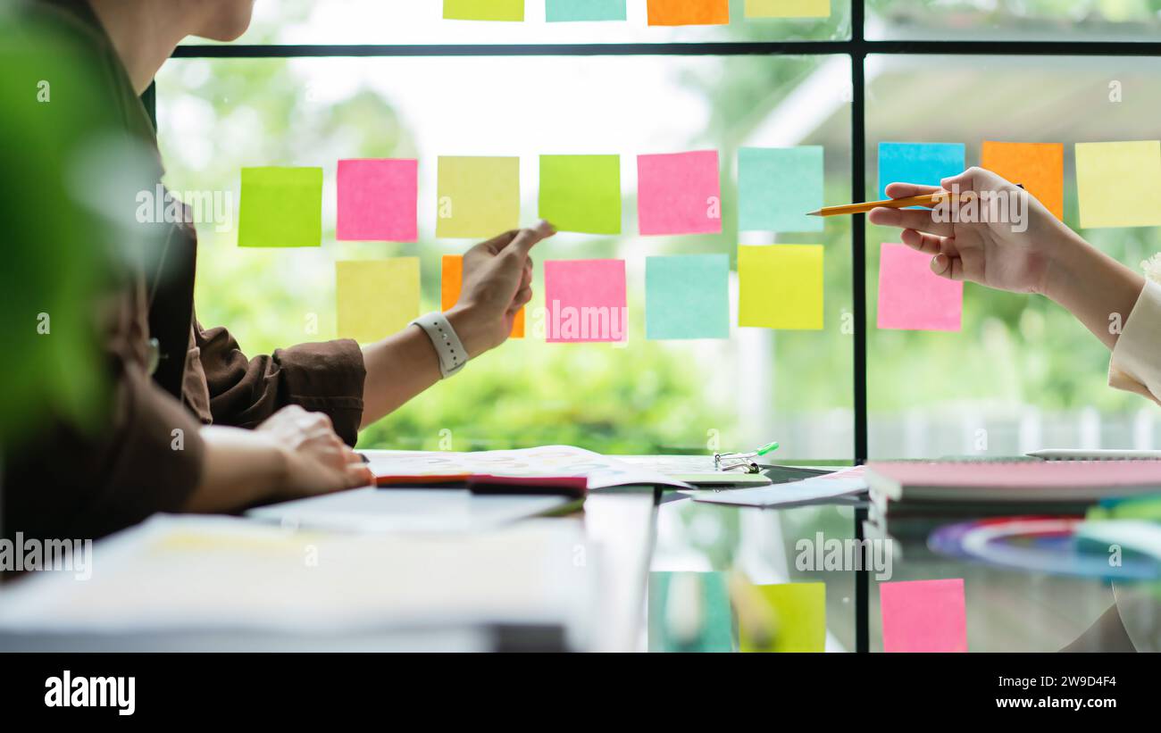Two creative graphic designers looking on sticky note to brainstorming ...