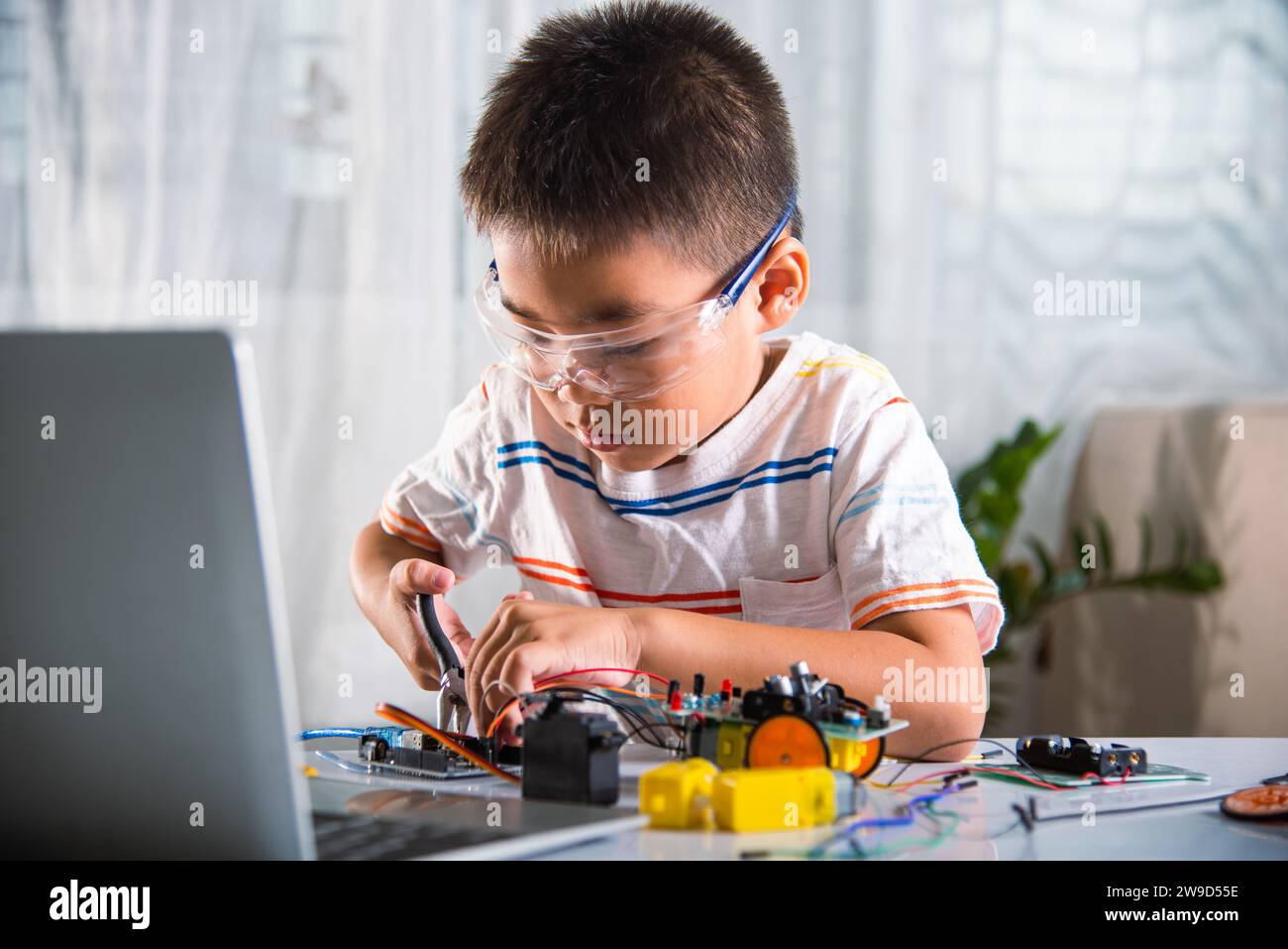 Asian kid boy assembling the Arduino robot car homework project at home ...