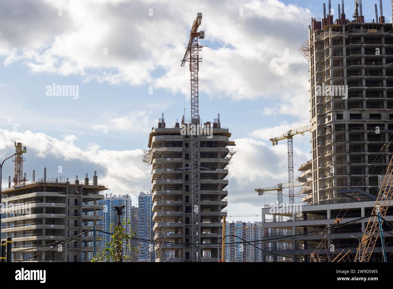 Minsk, Belarus - 9 september, 2023: Construction site with tall houses and cranes in sundown ...