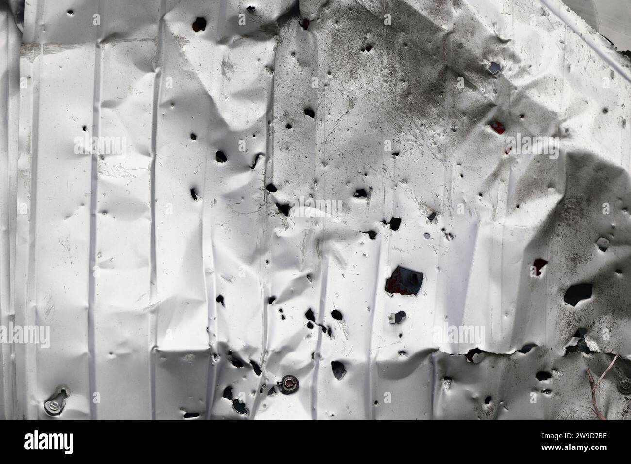 Holes from artillery shell fragments in the wall metal garage. Damage ...