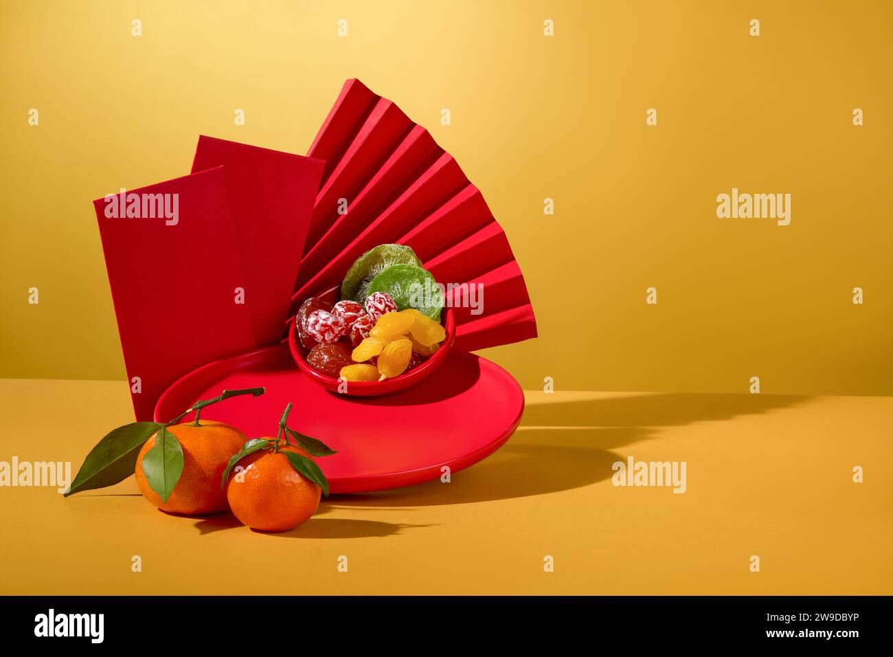 A dish of dried candy fruits displayed with envelopes, tangerines and a ...
