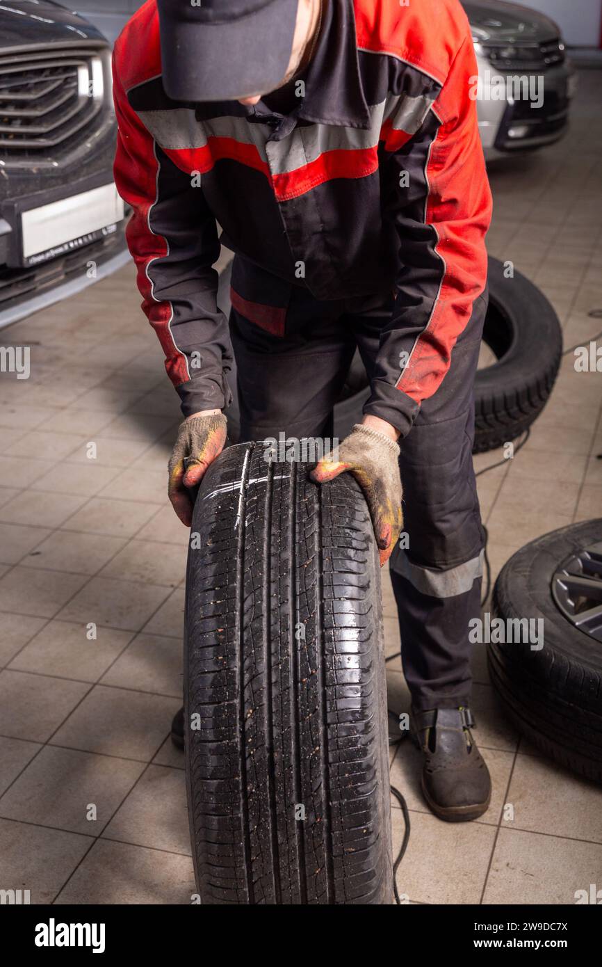 Repair service for wheel tire of car from big puncture. A worker keep a ...