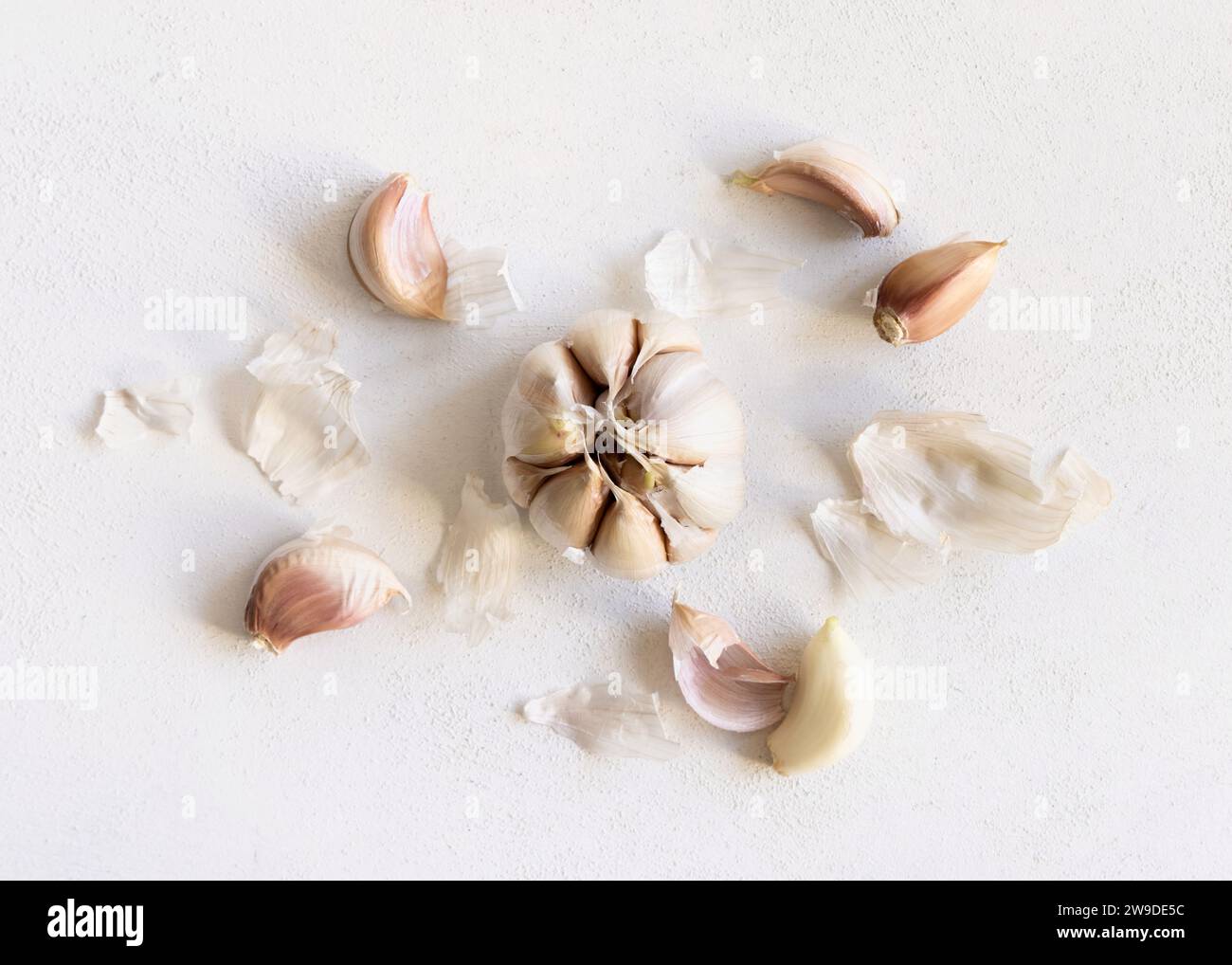 Fresh whole bulb of garlic, cloves and husk on a white table top view ...