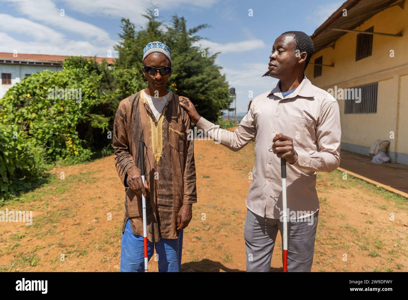 Blind man walking with his friend who is also blind touches his ...