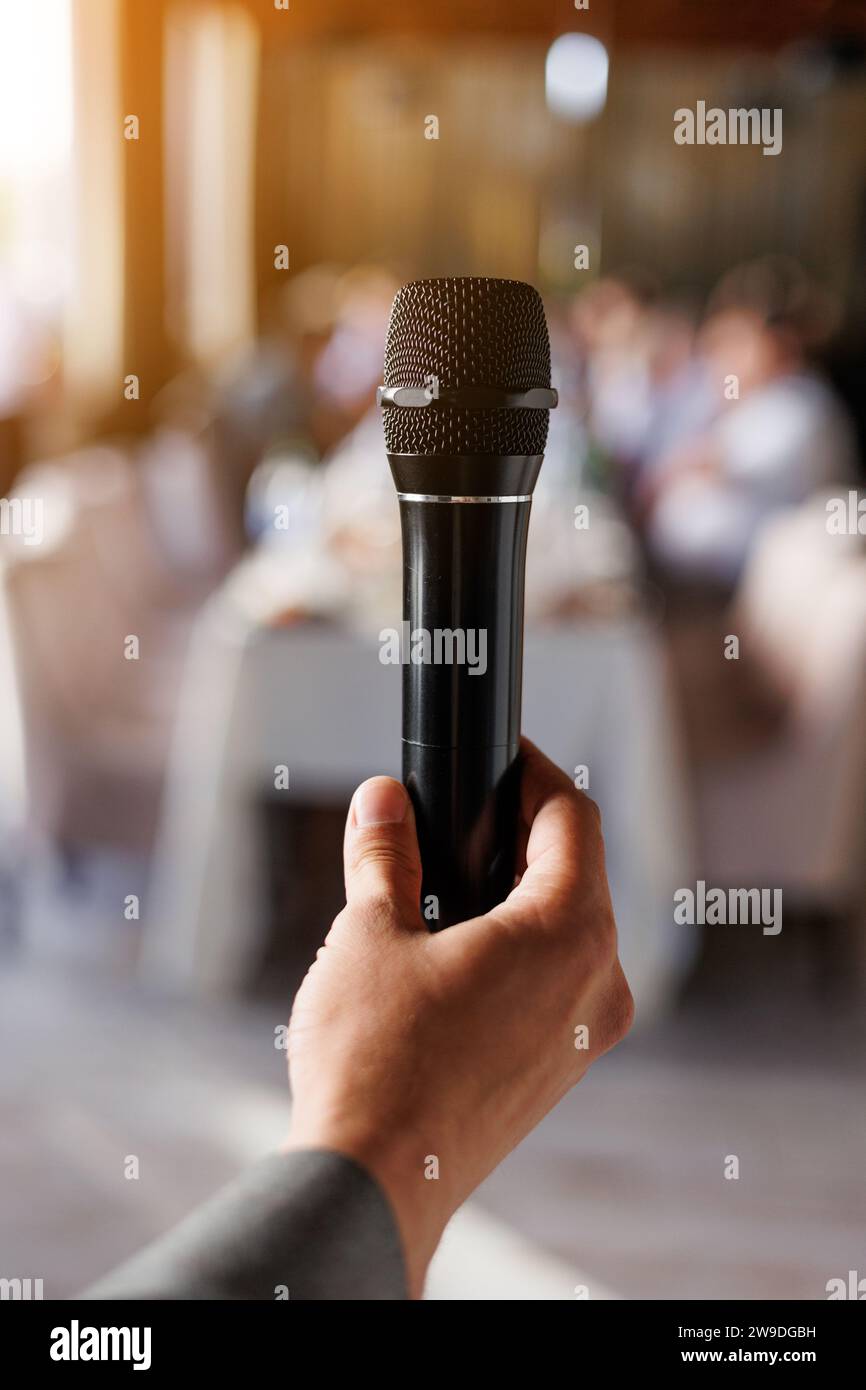 Unrecognisable male hand holds black microphone, master of ceremony or ...